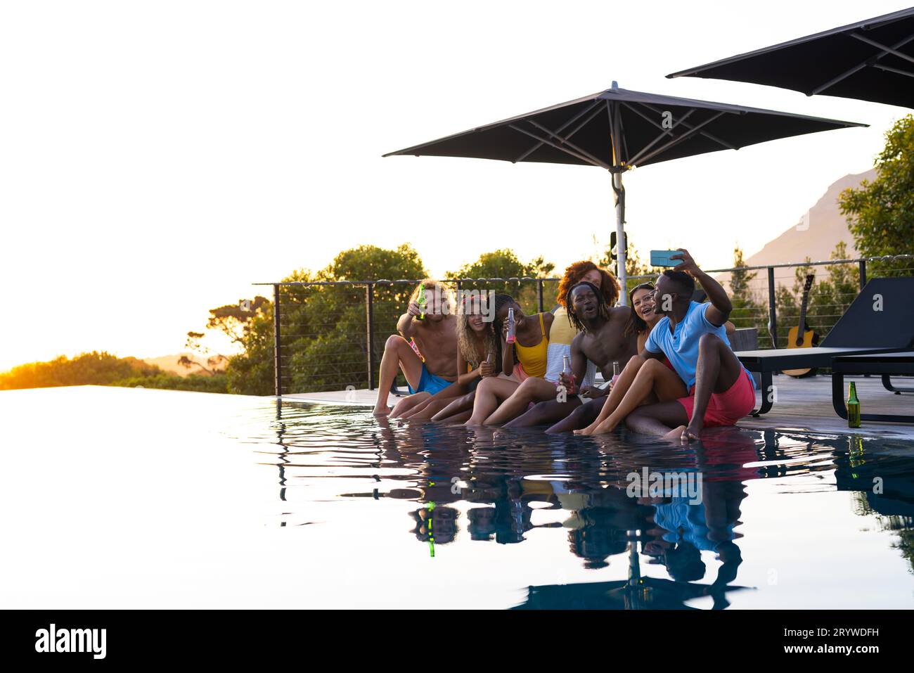 Happy diverse group of friends at pool party, drinking beer and taking ...