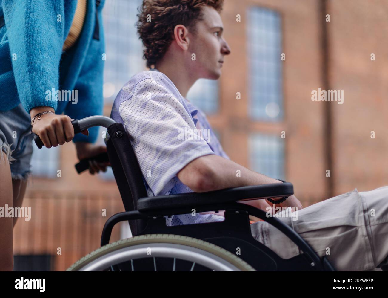 Sad gen Z boy in a wheelchair with friends in the city Stock Photo - Alamy