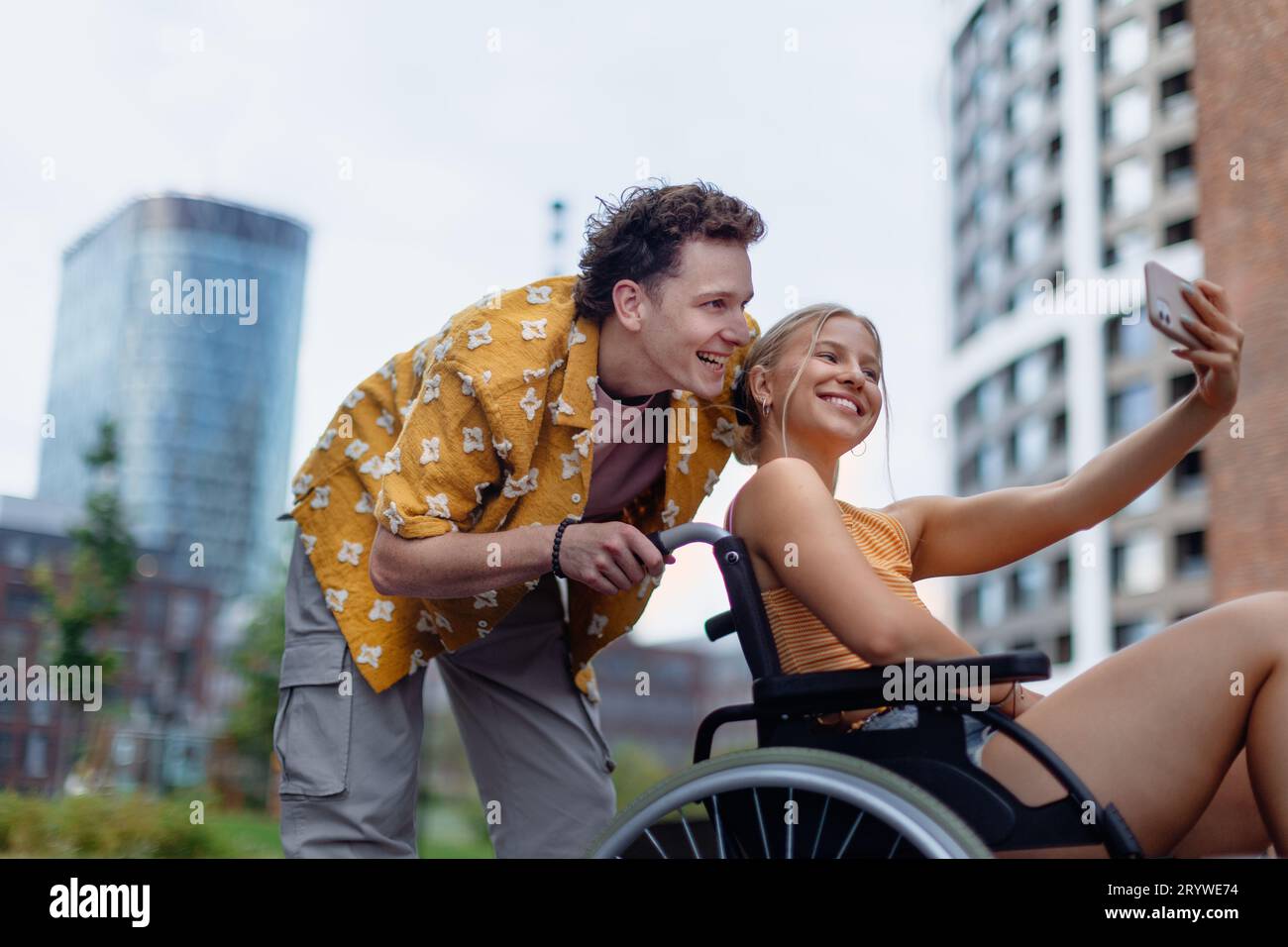 Beautiful gen Z girl in a wheelchair with her boyfriend taking selfie ...