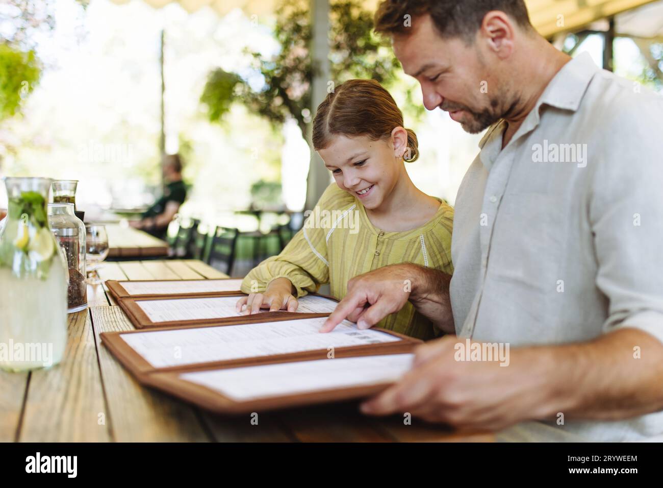 Father and daughter reading menus in a restaurant, choosing food and ...