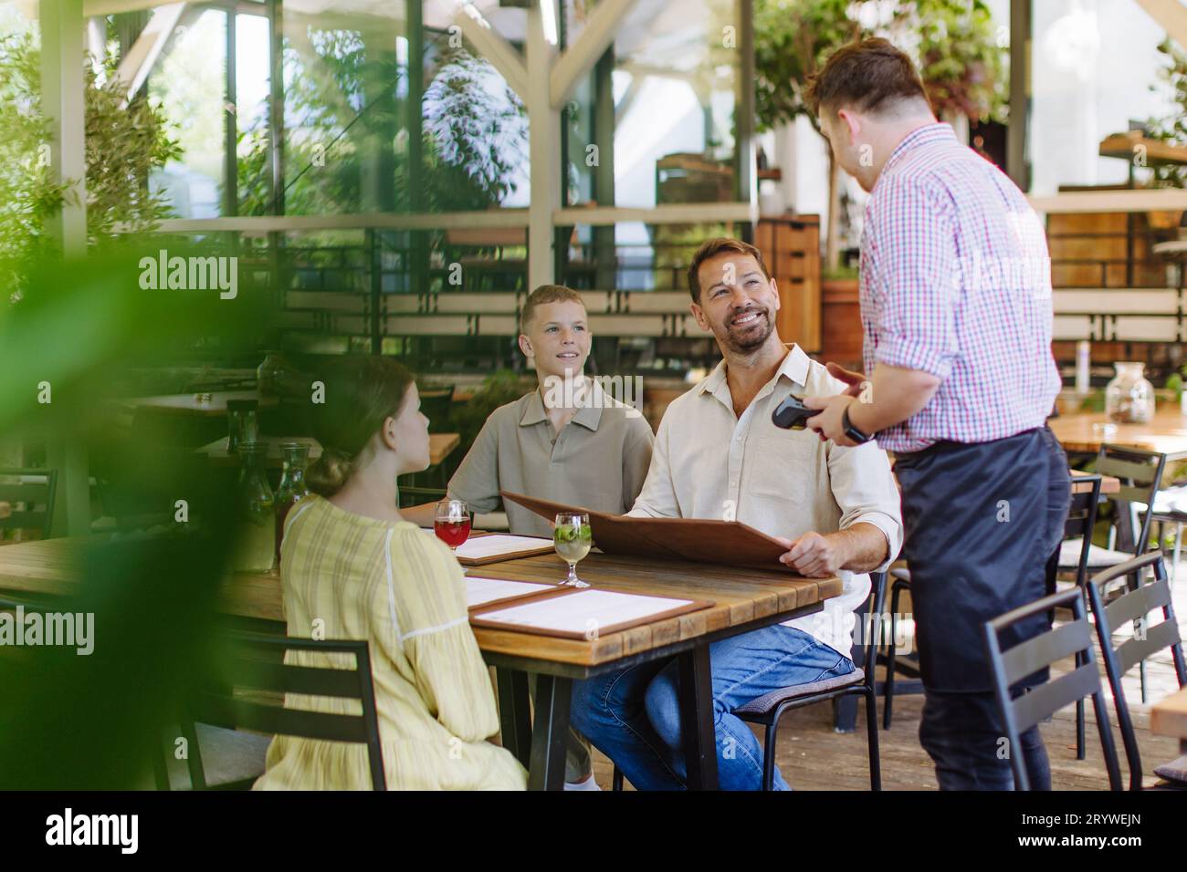 Father and children ordering food from a waiter Stock Photo - Alamy