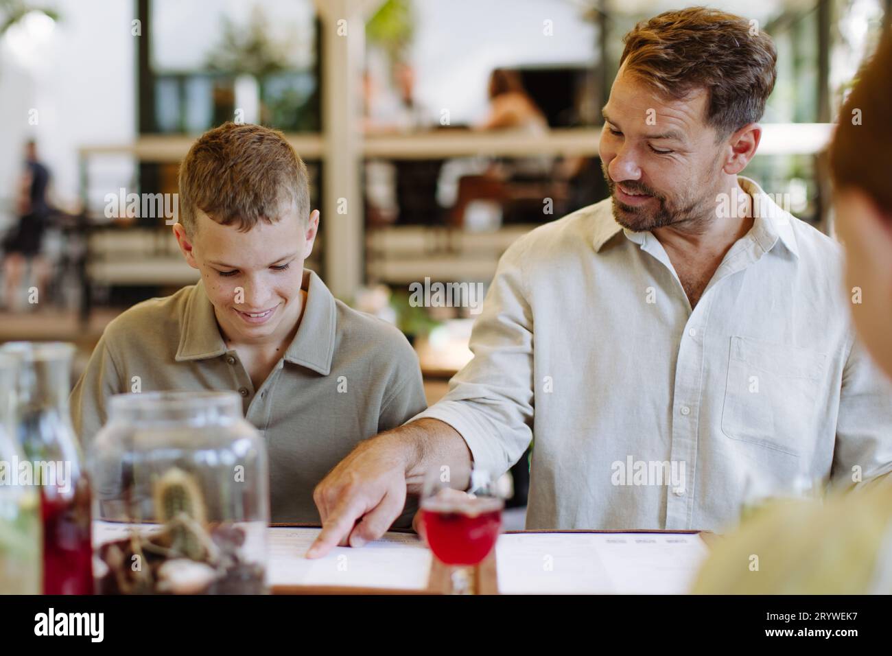 Father and son reading menus in a restaurant, choosing food and drinks ...