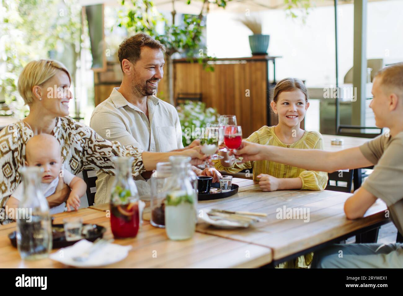 Big family with children and a small baby making toast at family dinner ...