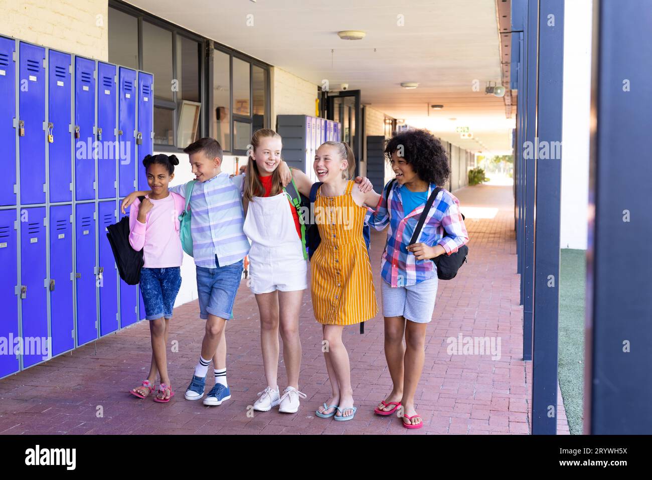 Happy group of diverse children standing with arms around shoulders in ...