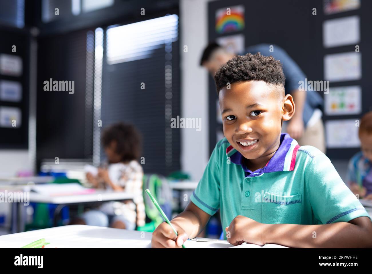 Smiling african american schoolboy working at desk in elementary school ...