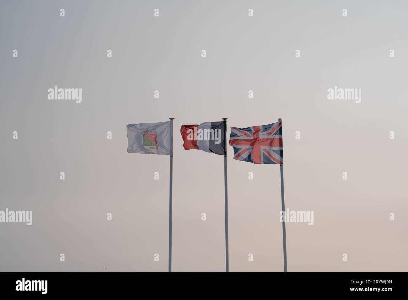 Three flags blowing in the wind: French, British and a white flag Stock ...