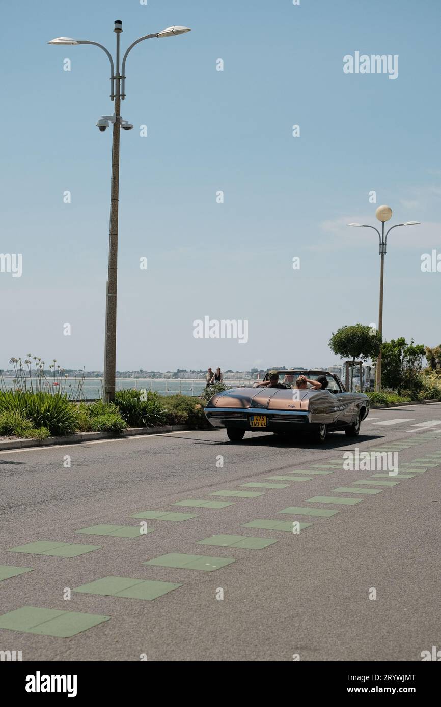 Three people sitting in a vintage car on an open road Stock Photo - Alamy