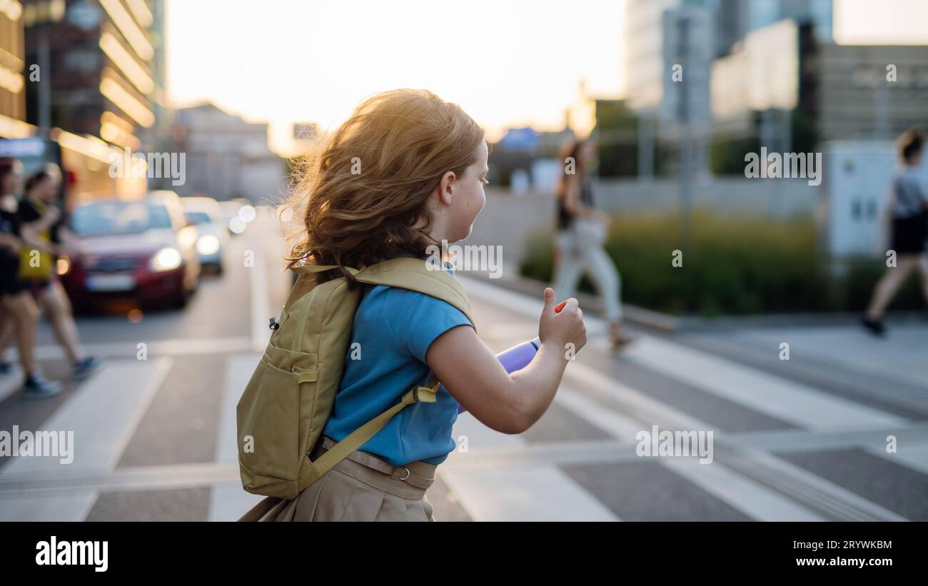 Side view of a girl with a backpack crossing the crosswalk on her way ...
