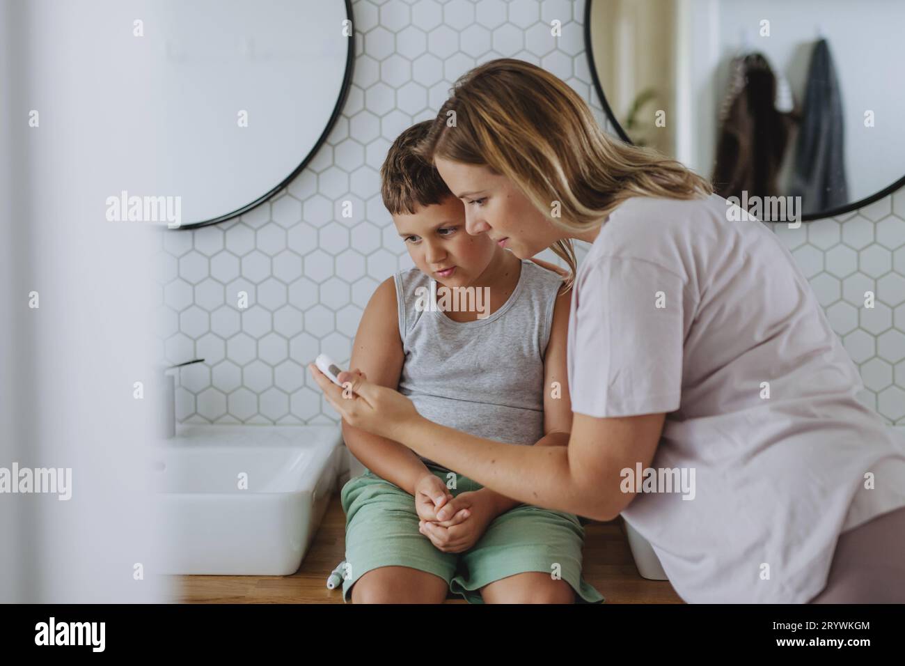 Mother checking her son's blood glucose level at home using a ...