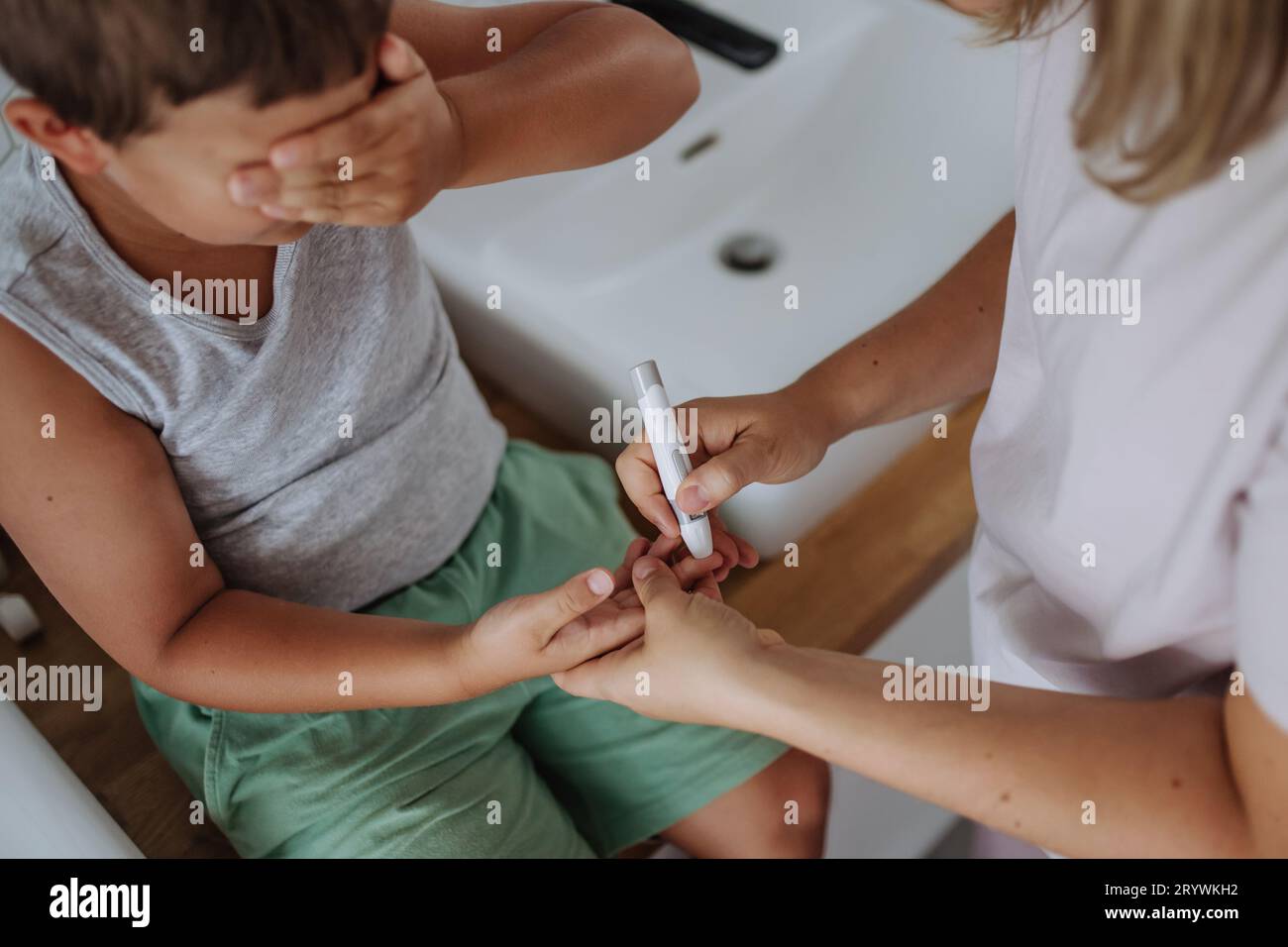 Mother checking her son's blood glucose level at home using a ...