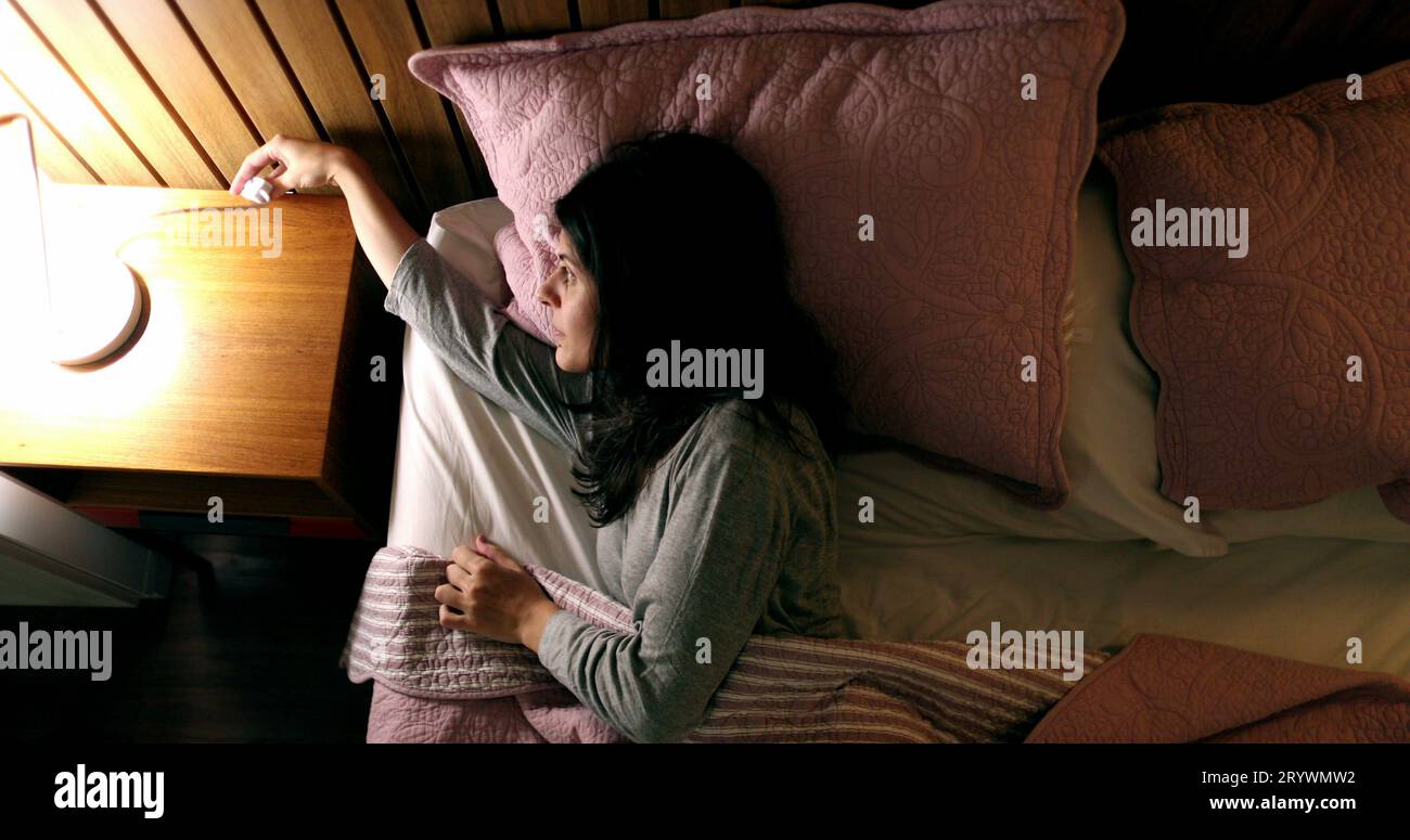 Single woman lying in bed turning off bedside lamp nightstand Stock ...