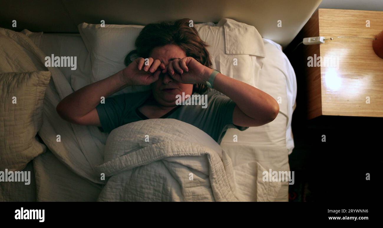Worried older woman lying in bed trying to sleep. Person suffering from ...