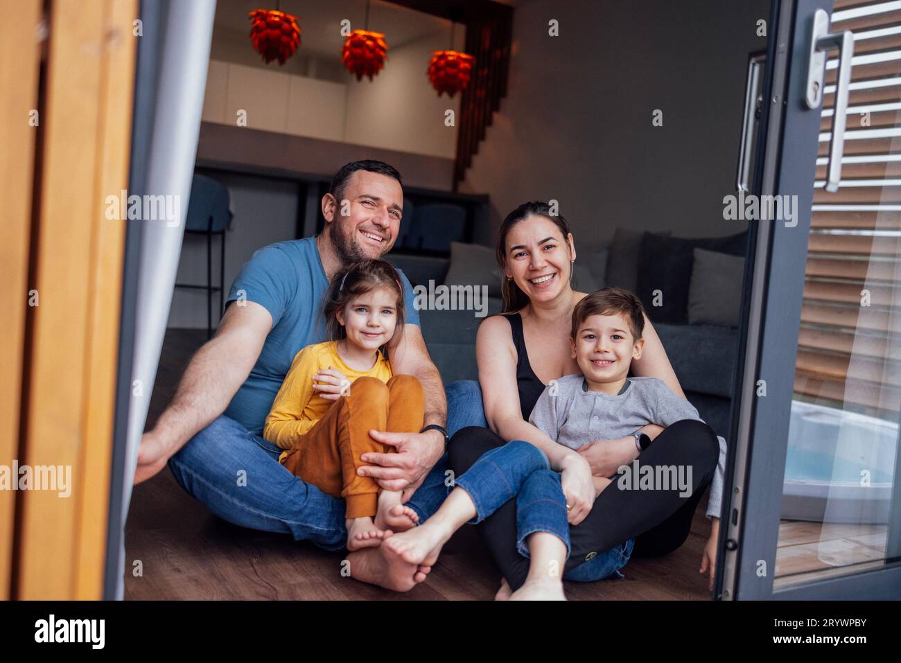 Young parents and small children sit on floor of living room at home in ...