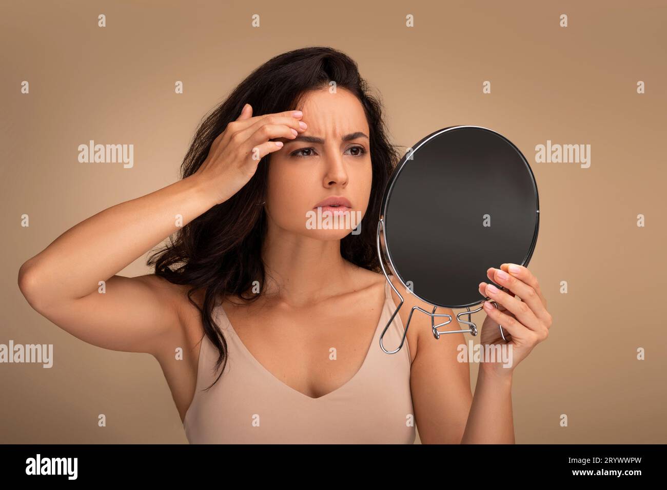 Concerned woman looking in mirror checking aging signs on face Stock ...