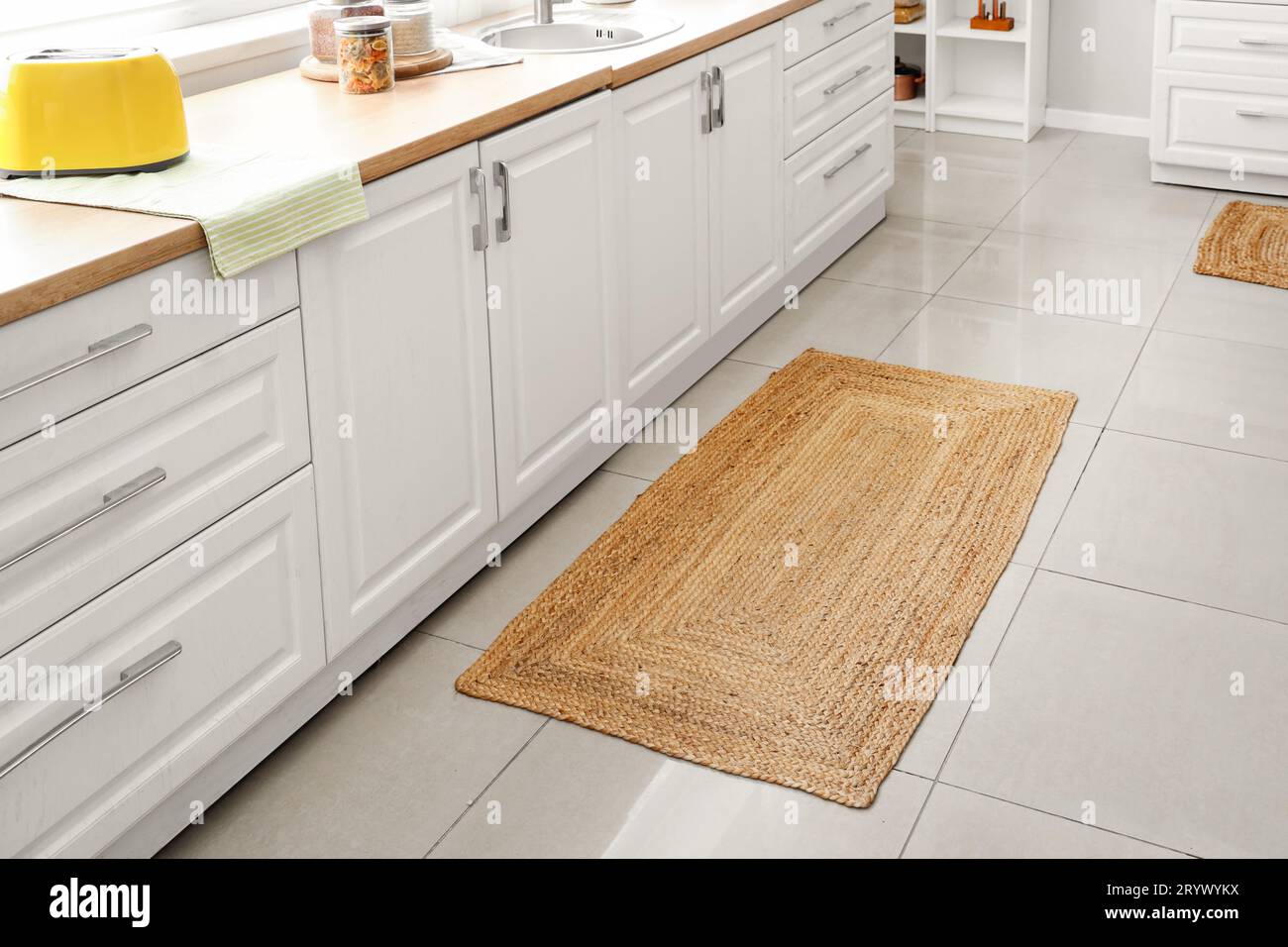 Interior of light kitchen with white counters and wicker carpet Stock ...