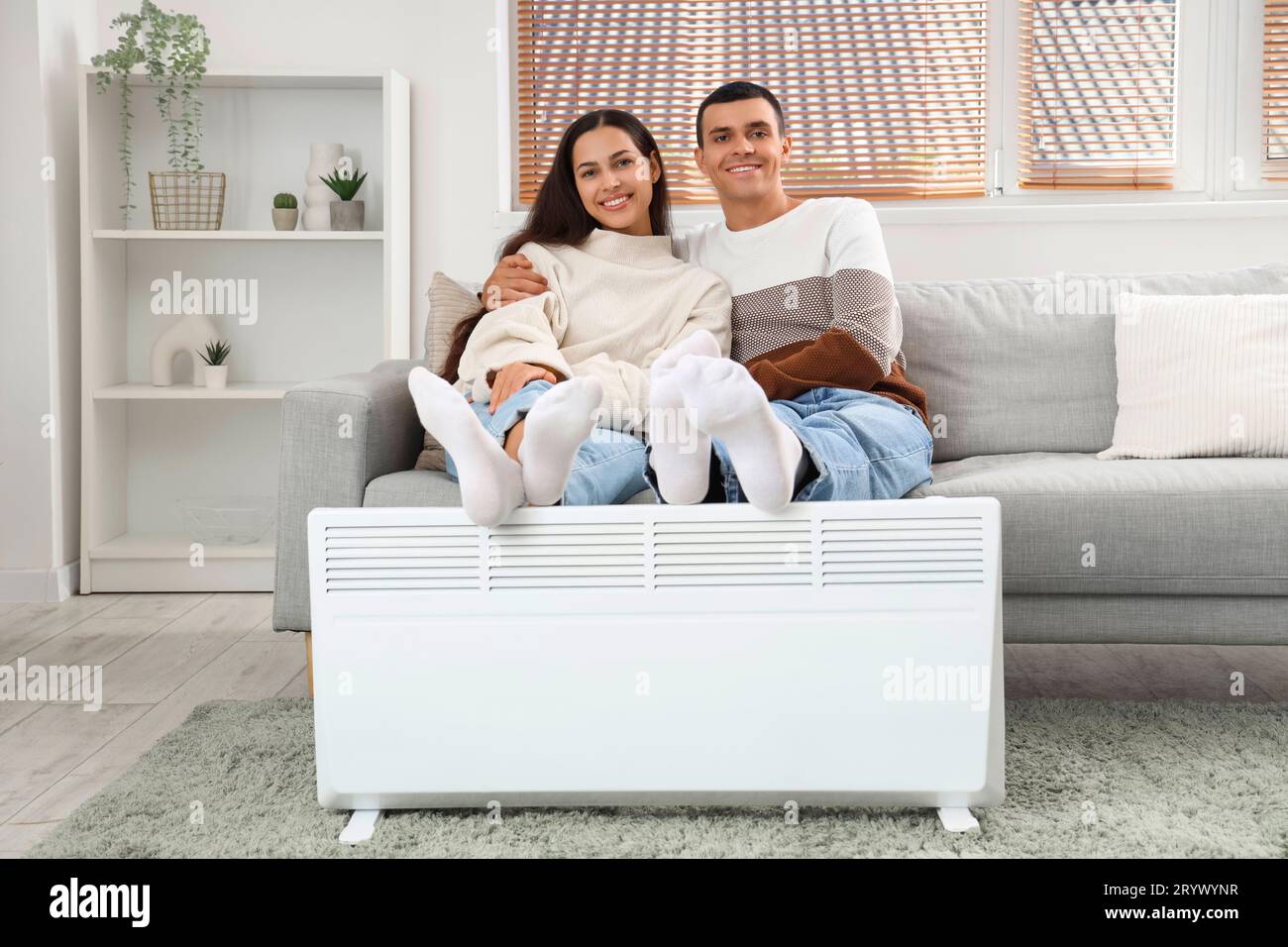 Young couple warming legs on radiator at home Stock Photo - Alamy