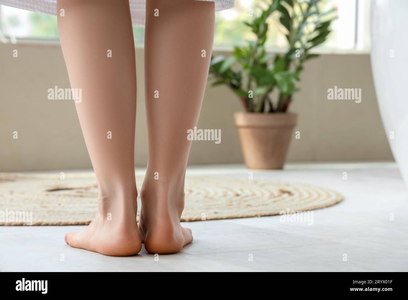 Barefoot woman in bathroom with floor heating, back view Stock Photo ...