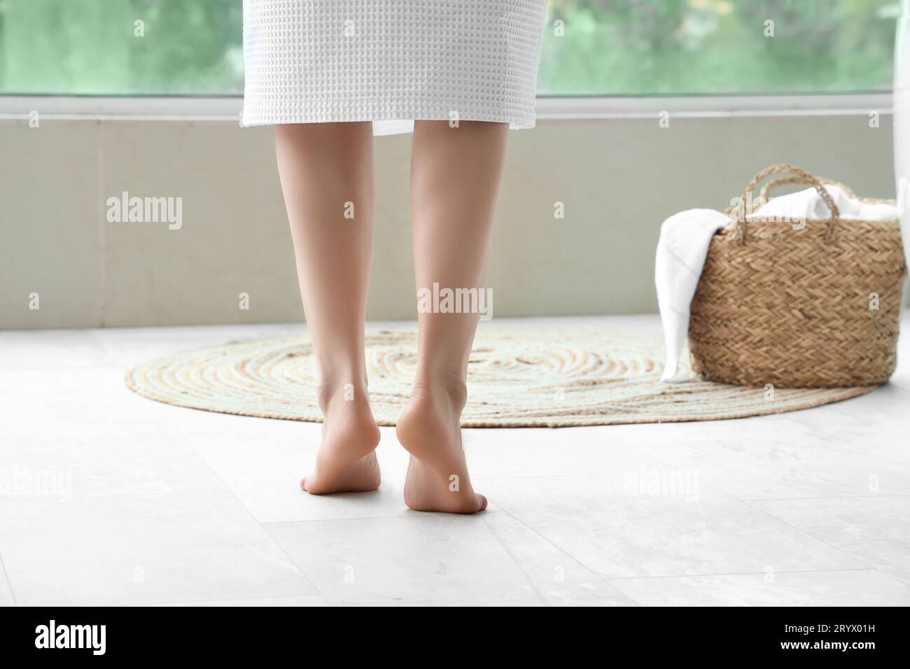 Barefoot woman walking in bathroom with floor heating, back view Stock ...