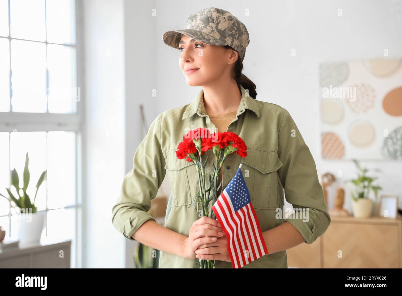Female soldier with USA flag and carnation flowers at home. Veterans ...