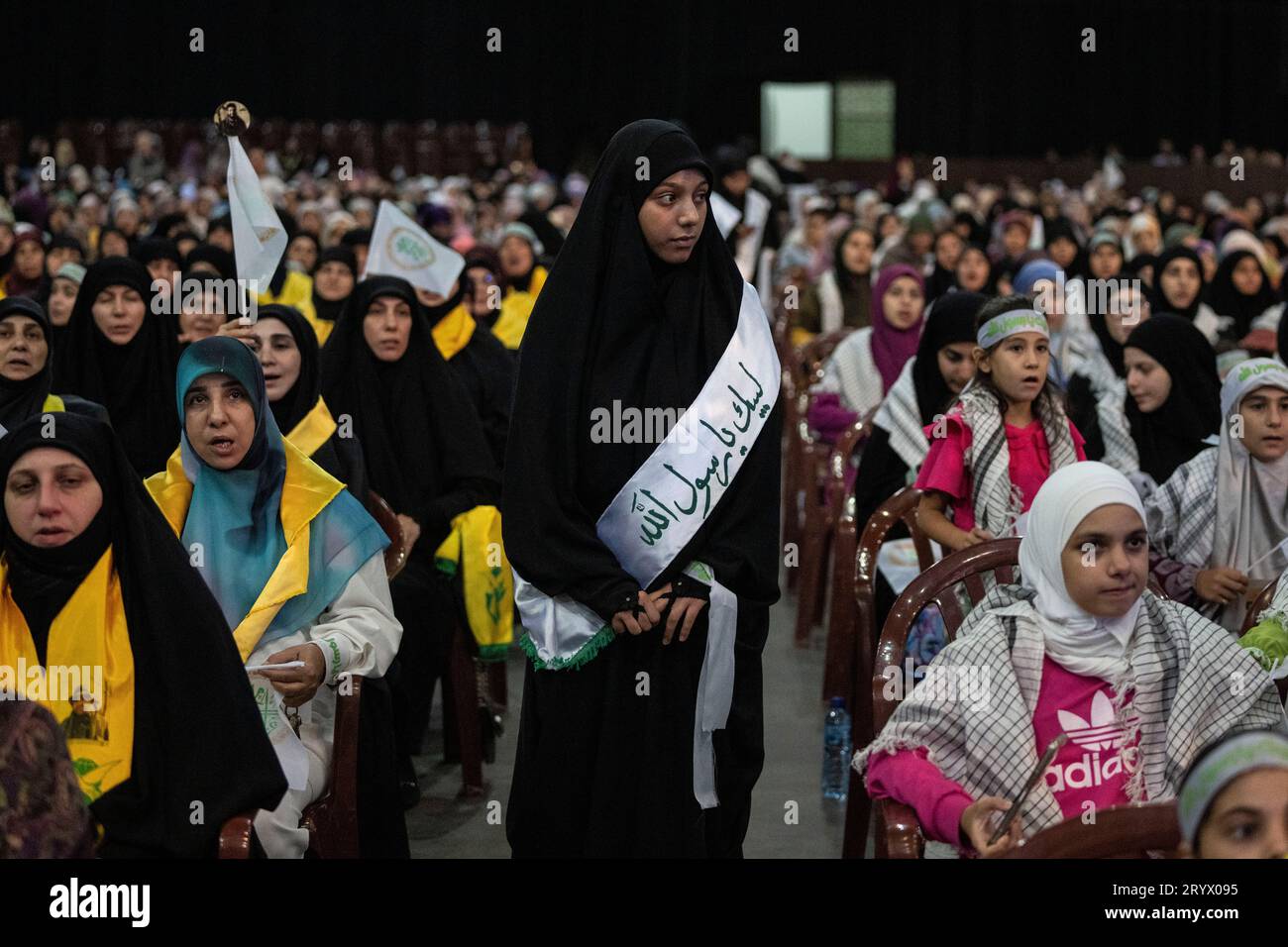 A Hezbollah supporter, center, wears a scarf with Arabic that reads ...
