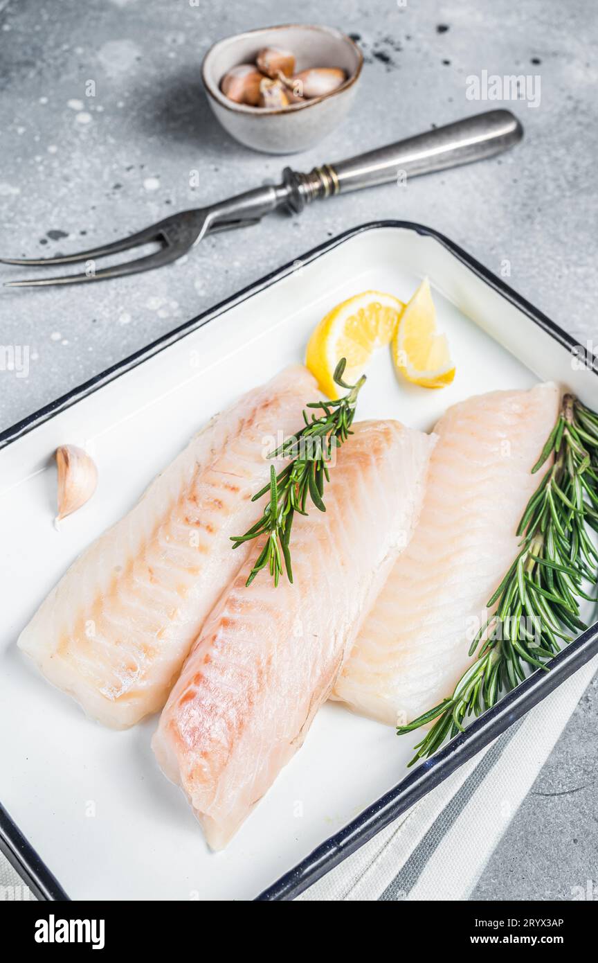 Uncooked Raw cod loin fillet steaks with herbs in kitchen tray. Gray ...
