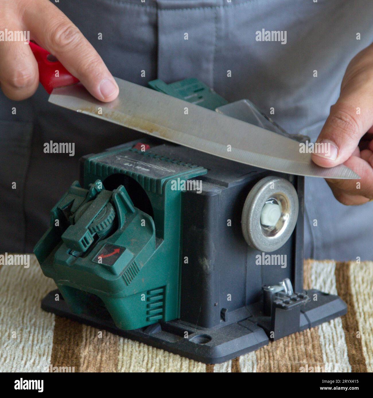 Image of a shoemaker sharpening a kitchen knife with a sharpening wheel ...