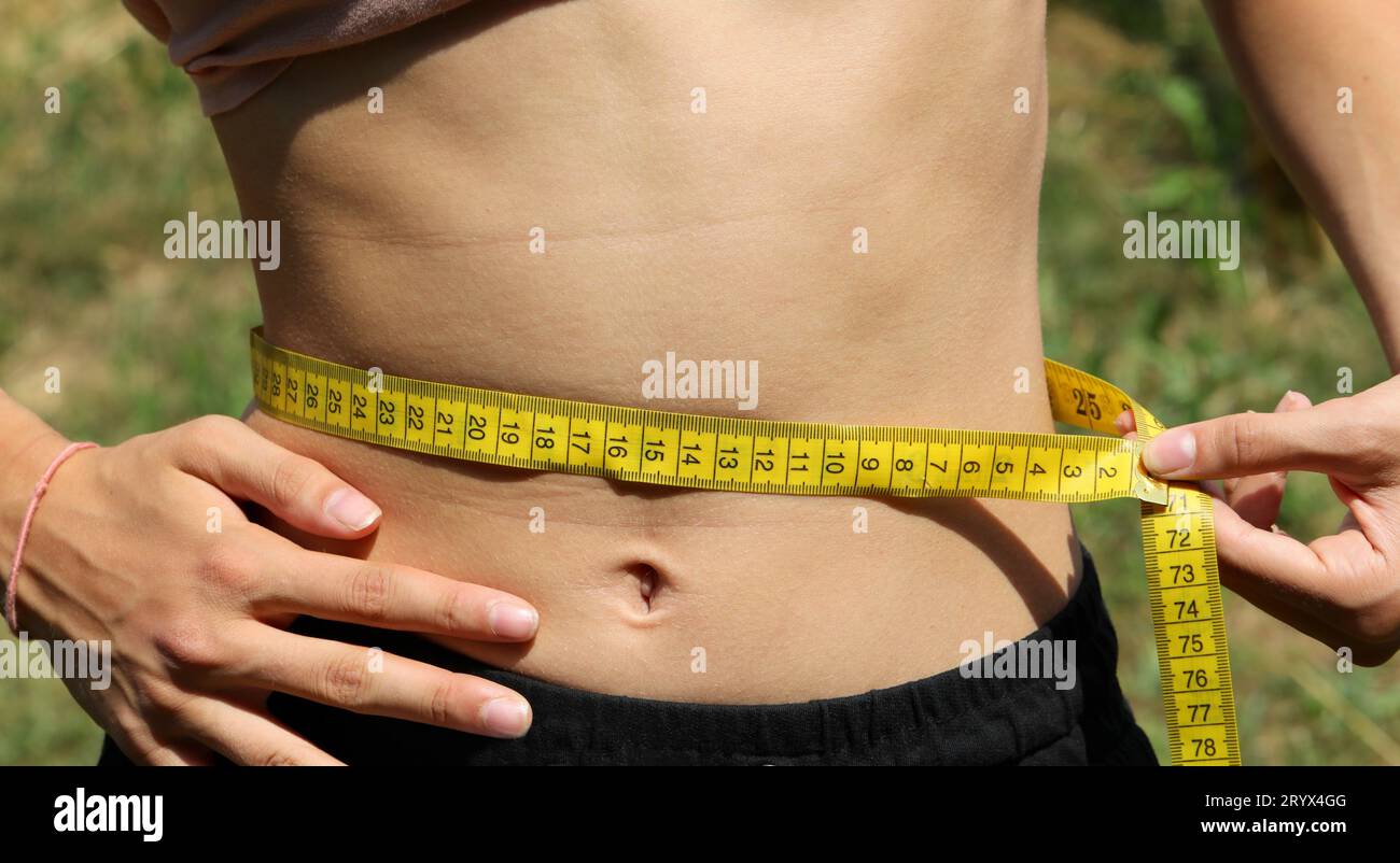 girl with yellow meter while measuring waistline and numbers in ...