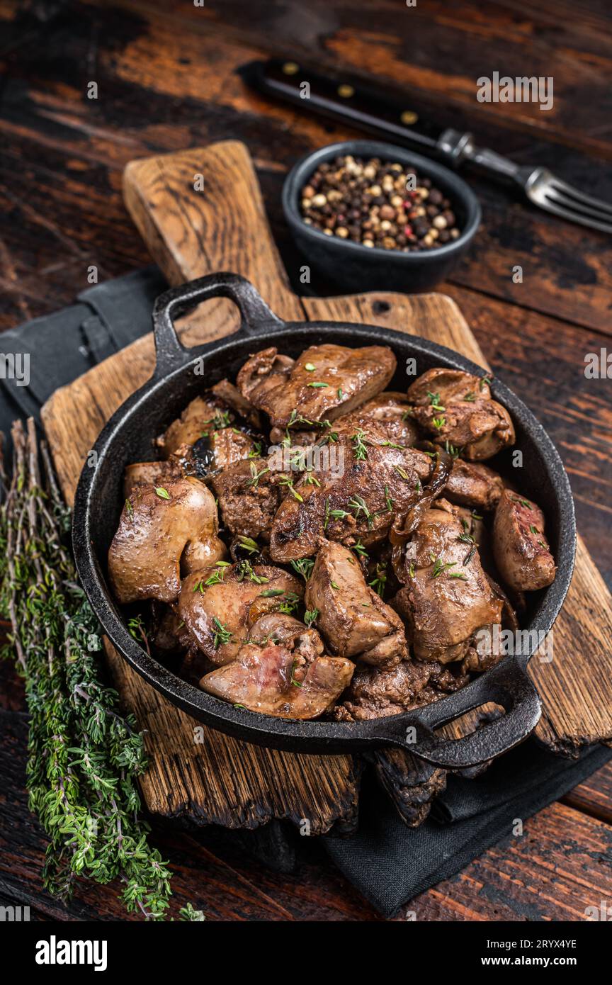 Roasted chicken liver with onions in a skillet. Wooden background. Top ...