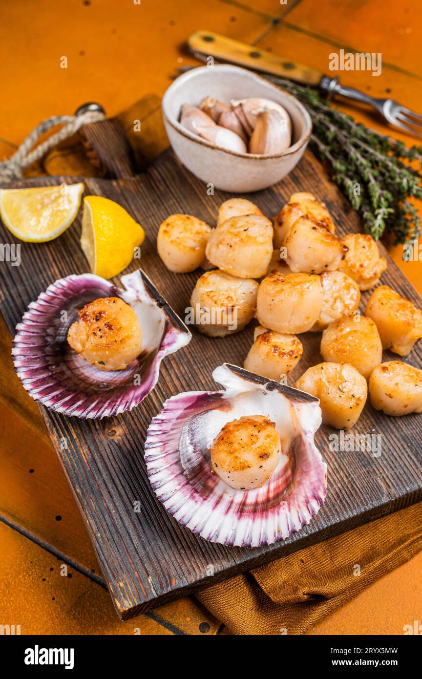 Seared Scallops fillets on a wooden board ready for eat. Orange ...