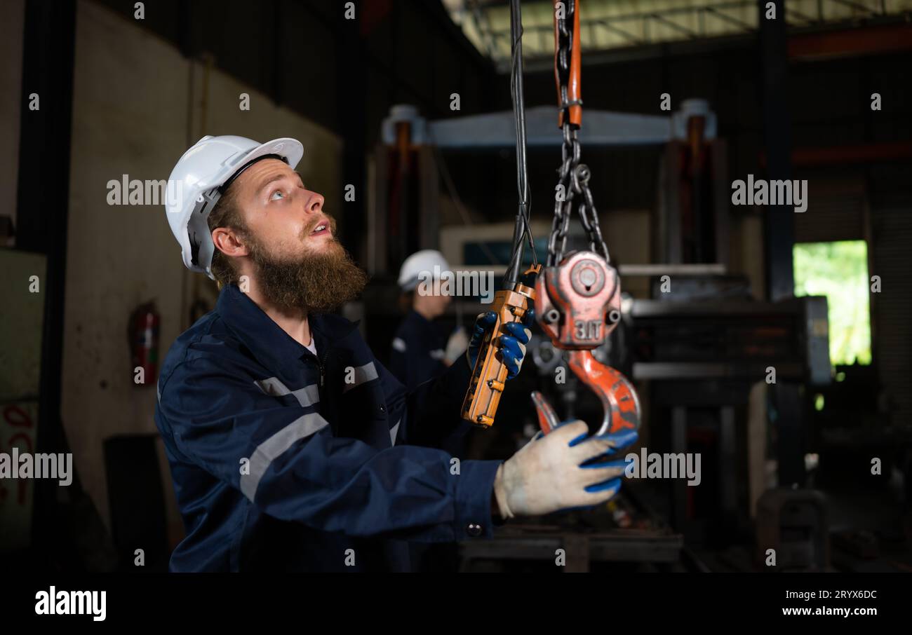 Two technicians inspecting and testing the operation of lifting cranes ...