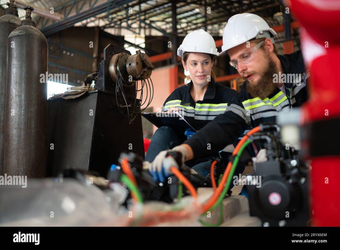 Both of engineers installing a small robotic arm is being installed for ...