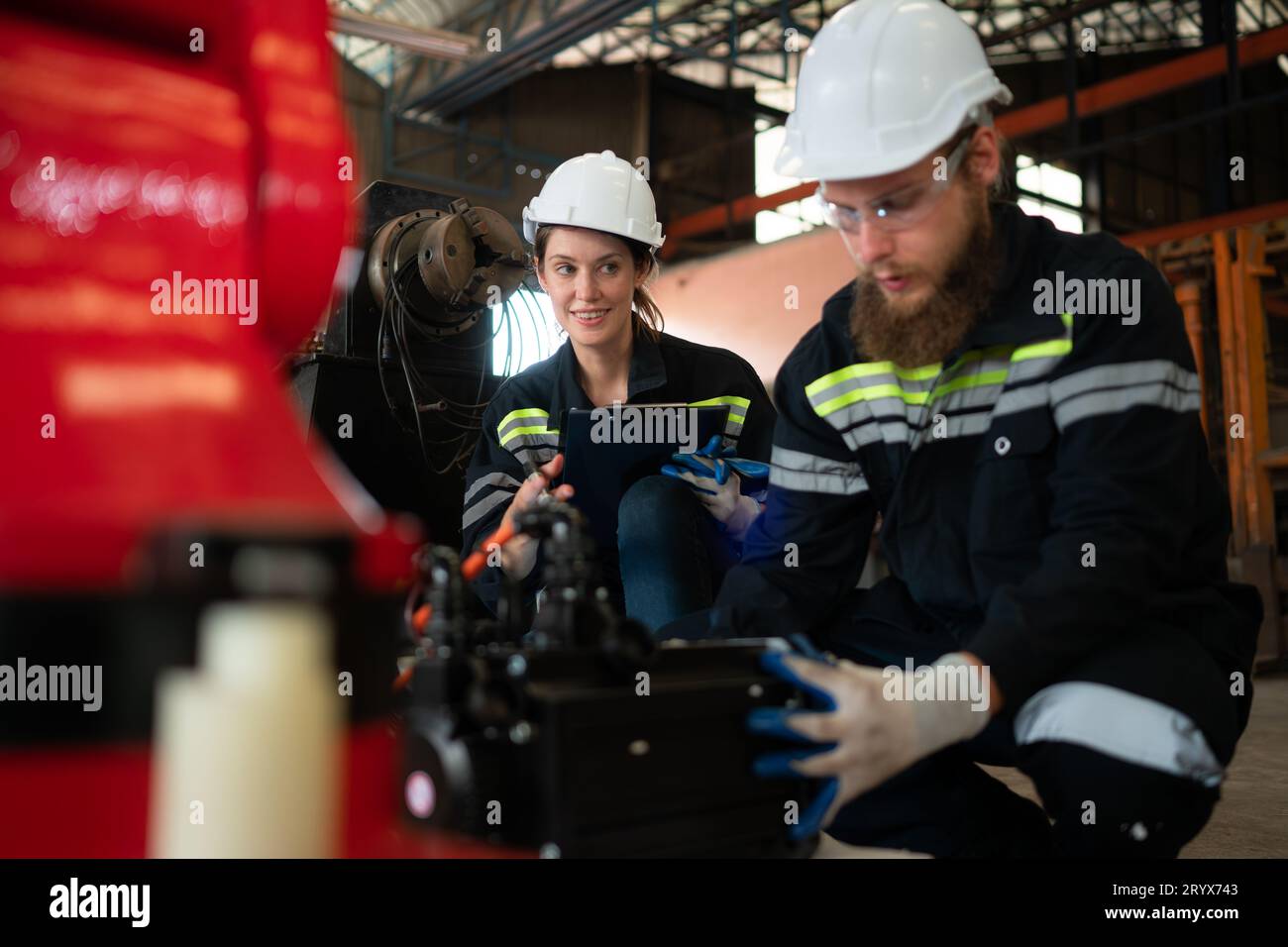 Both of engineers installing a small robotic arm is being installed for ...