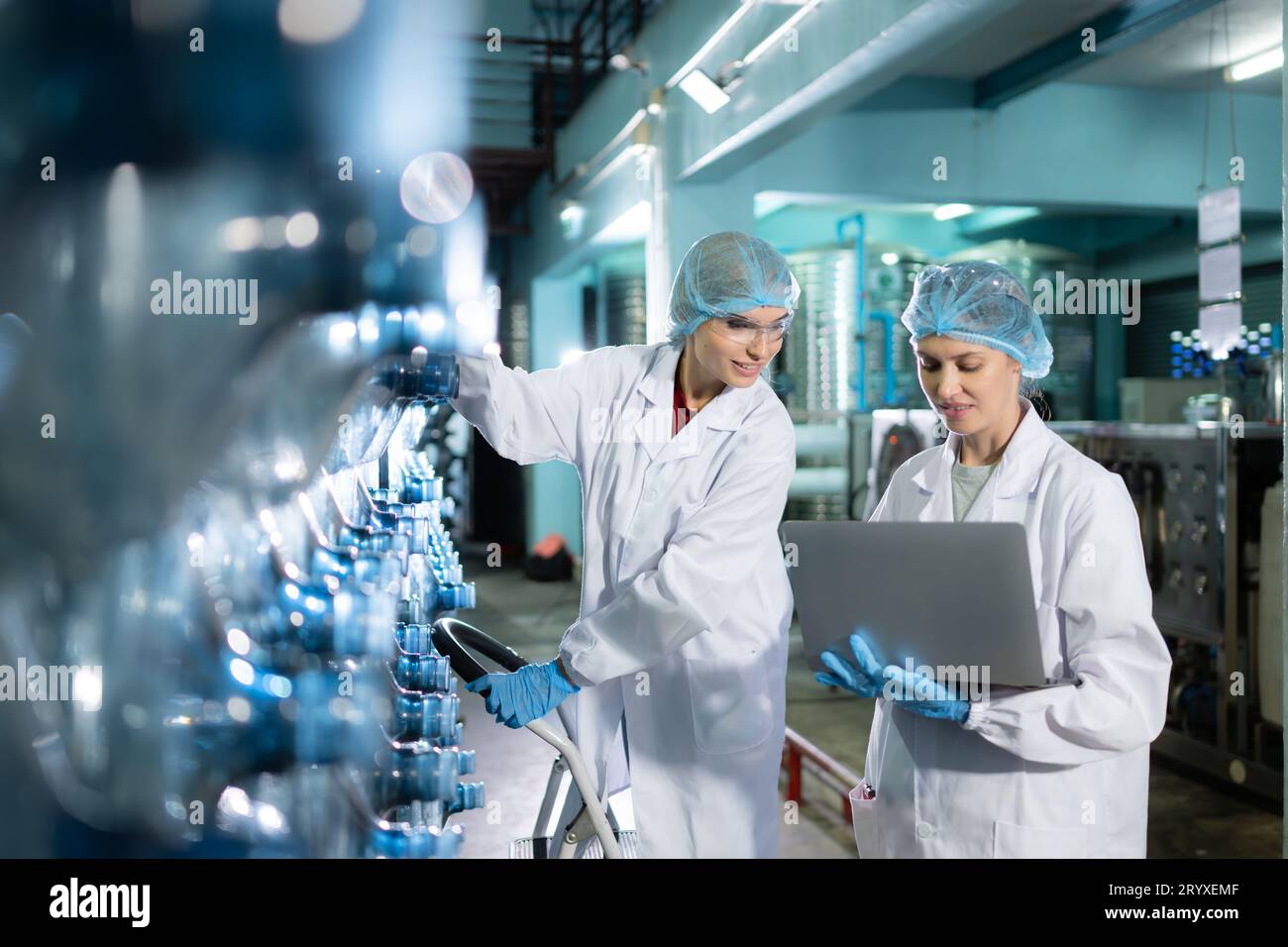 Portrait of a scientist in the drinking water factory using a ladder ...