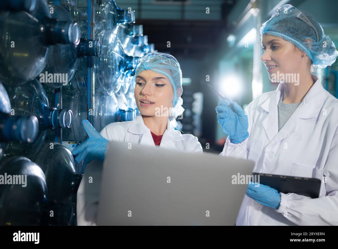 Two young female scientists working with tablet computer in drinking ...