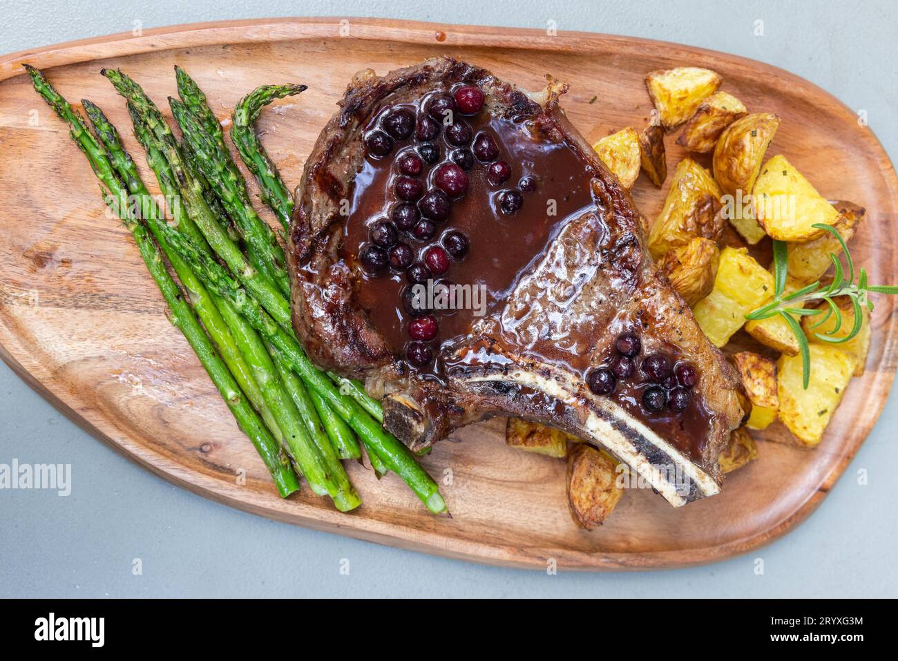 Grilled bone in ribeye served with potatoes and asparragus topped with ...