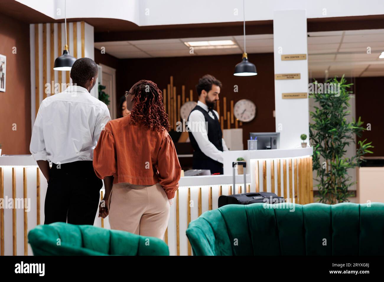 Travelling couple arriving at hotel reception desk, holding hands in ...
