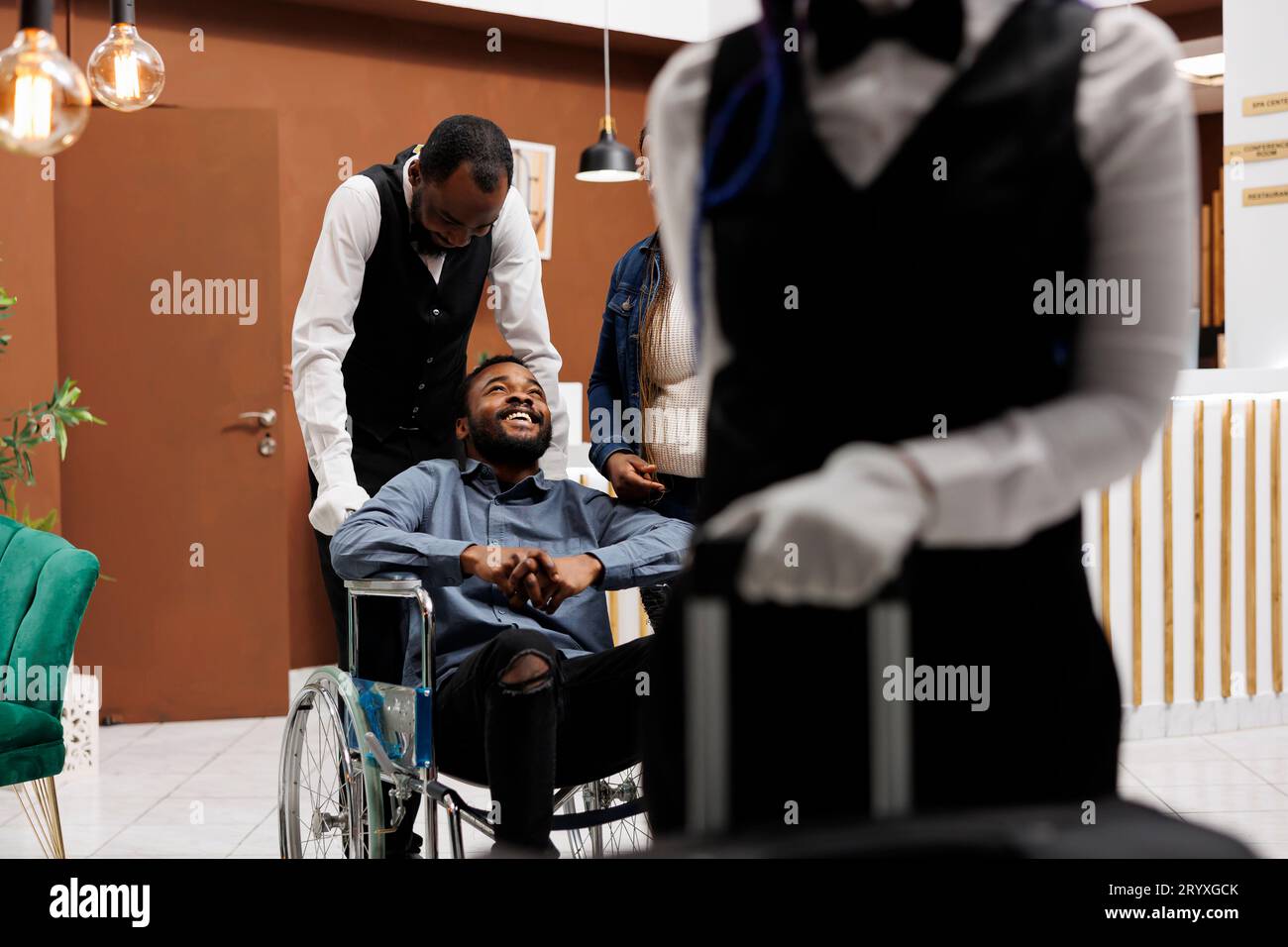 Wheelchair-friendly travel. Helpful hotel staff helping happy young ...