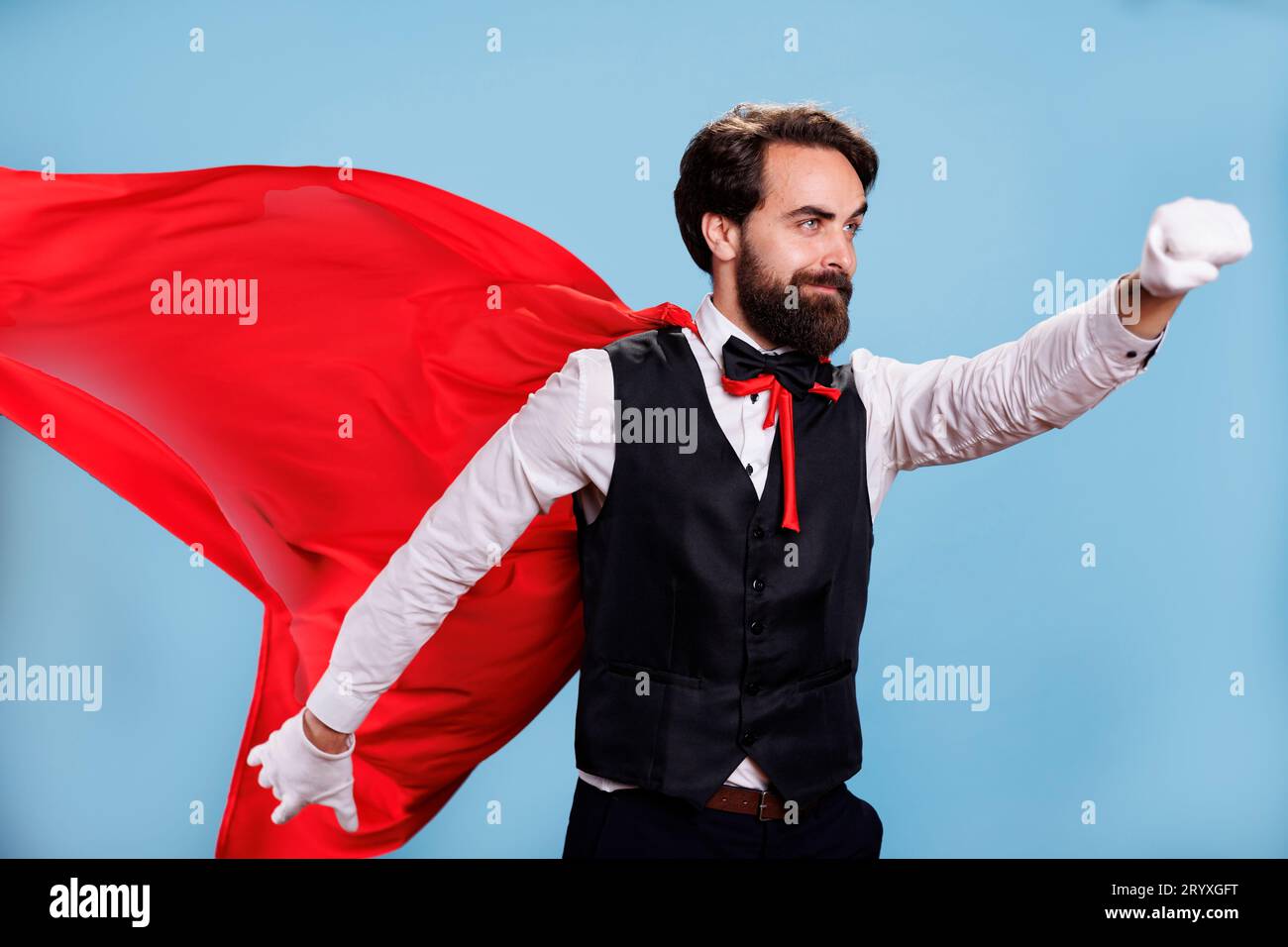 Determined adult posing as superhero while he wears red mantle against ...