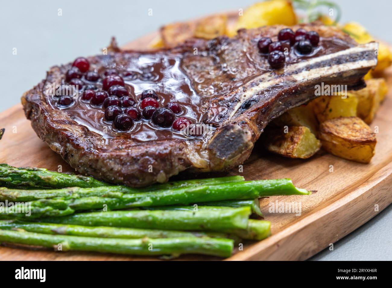 Grilled bone in ribeye served with potatoes and asparragus topped with ...