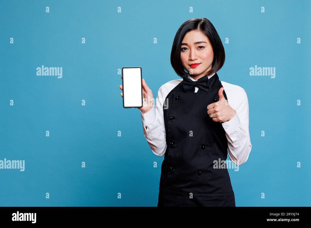 Young asian woman cafe worker presenting smartphone empty screen mockup ...