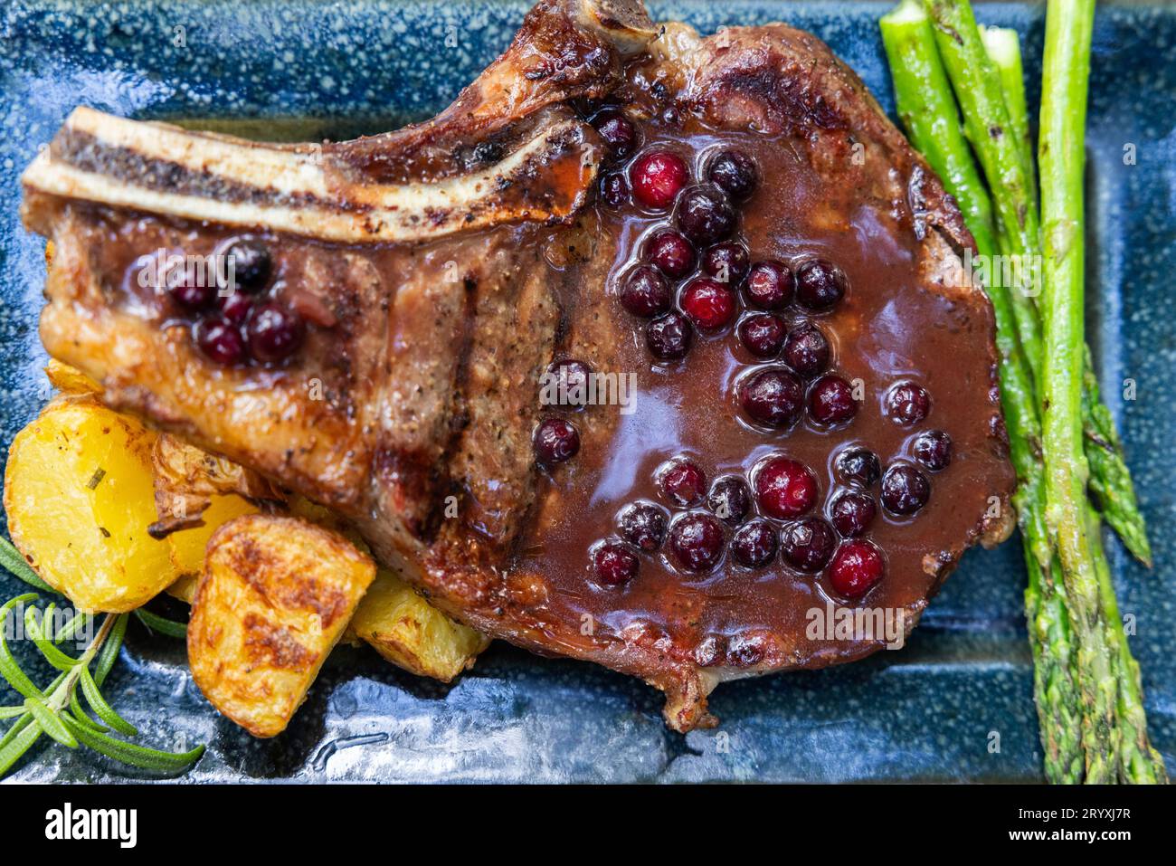 Grilled bone in ribeye served with potatoes and asparragus topped with ...