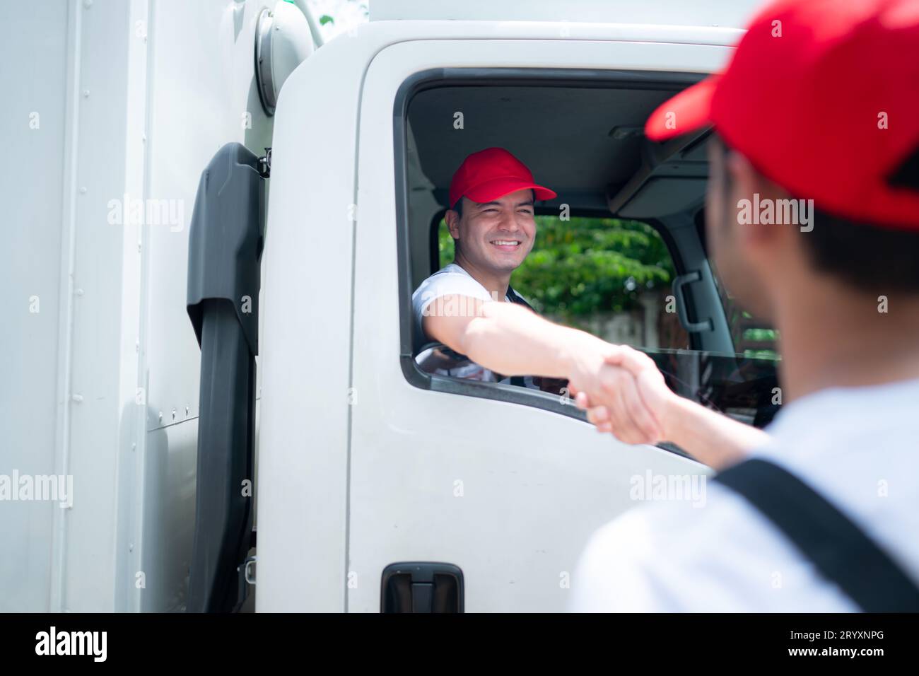 Delivery man in red cap and uniform handshaking each other after ...