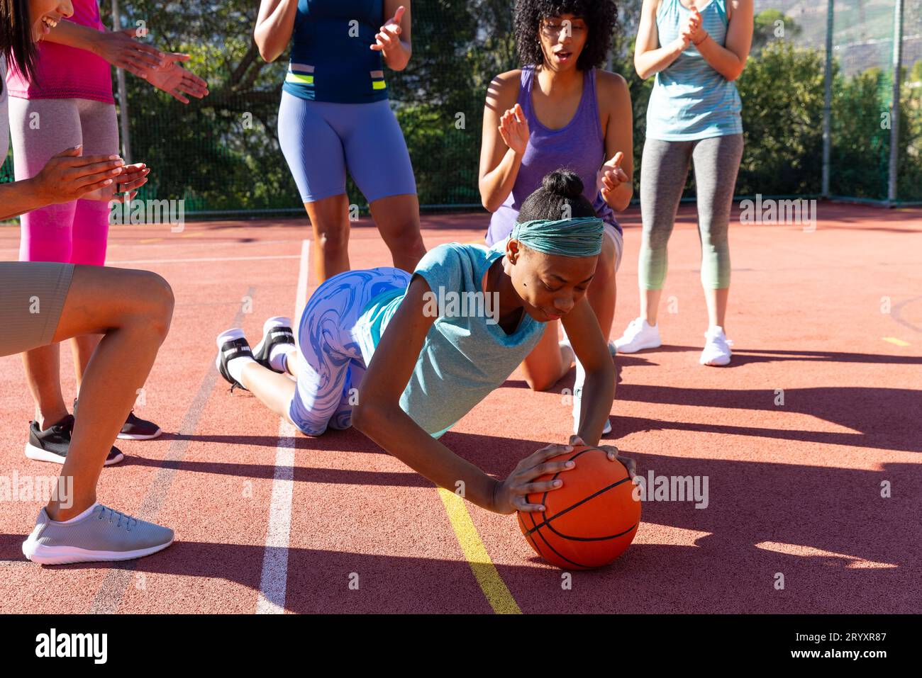 Happy diverse group of women doing push ups with basketball and ...