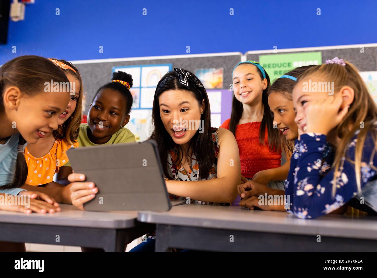 Diverse female teacher with tablet and elementary schoolgirls in class ...