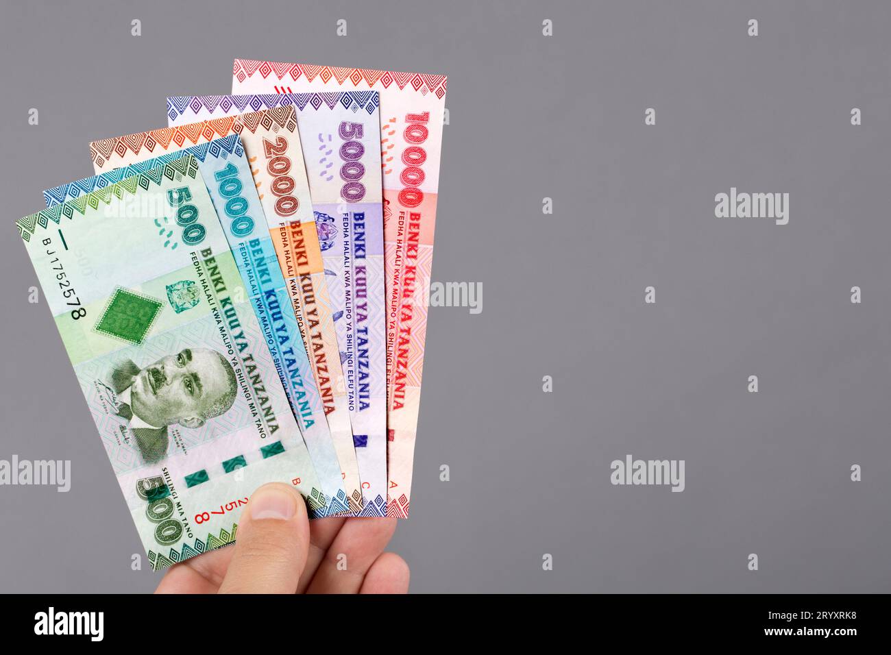 Tanzanian money in the hand on a gray background Stock Photo - Alamy