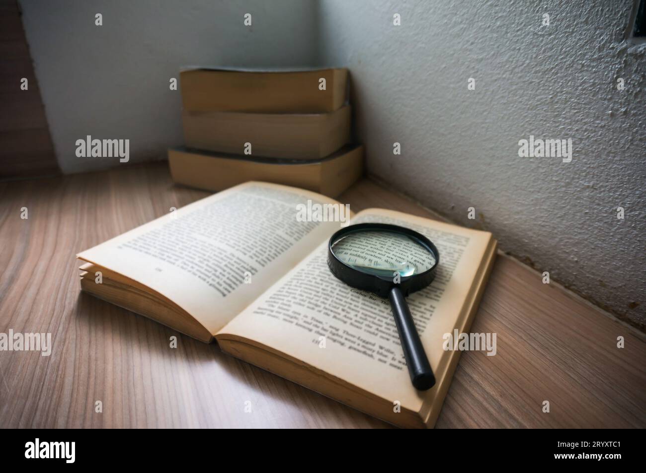 Books and a magnifier Research concept. Magnification glass over opened ...