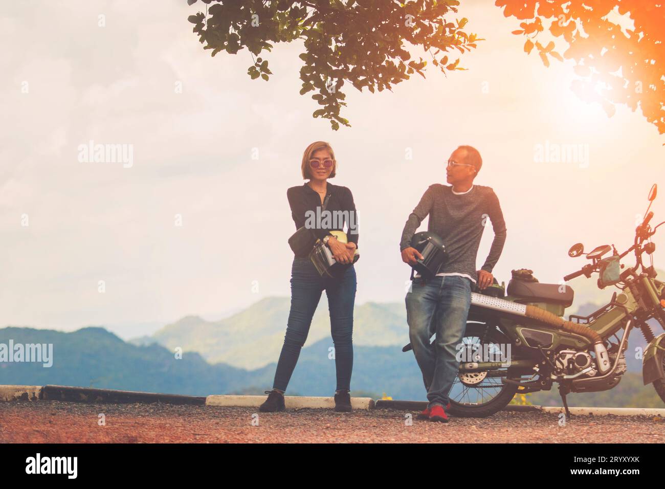 couples holding safety helmet sitting on small enduro motorcycle ...