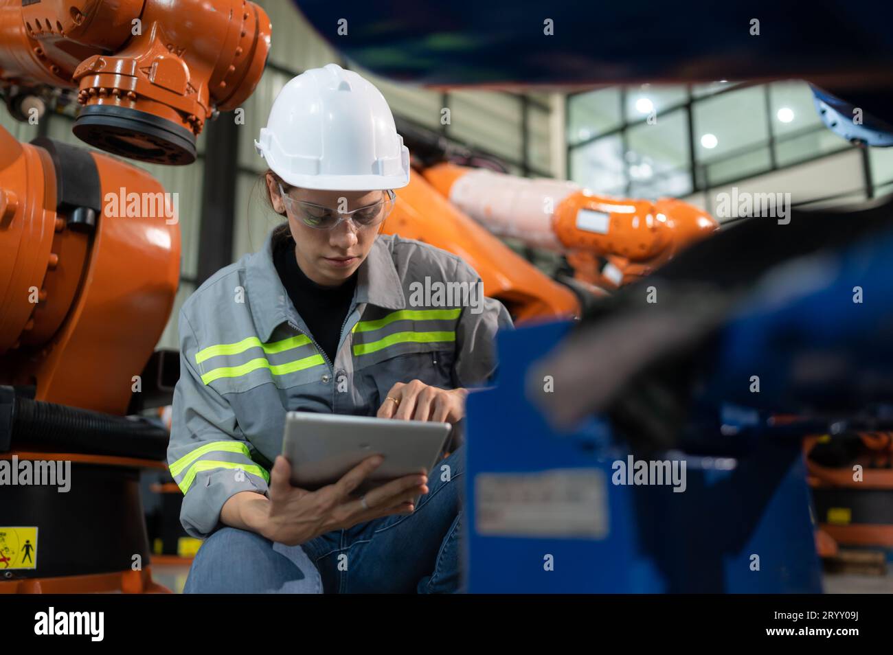 A female engineer installs a program on a robotics arm in a robot ...