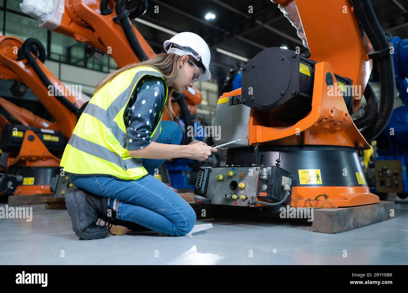 Female Technician Inspecting and repairing robotics arm in robots ...