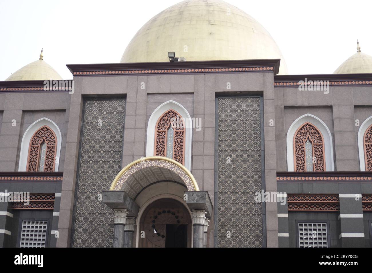The mosque building with a golden yellow dome appears under a clear sky ...